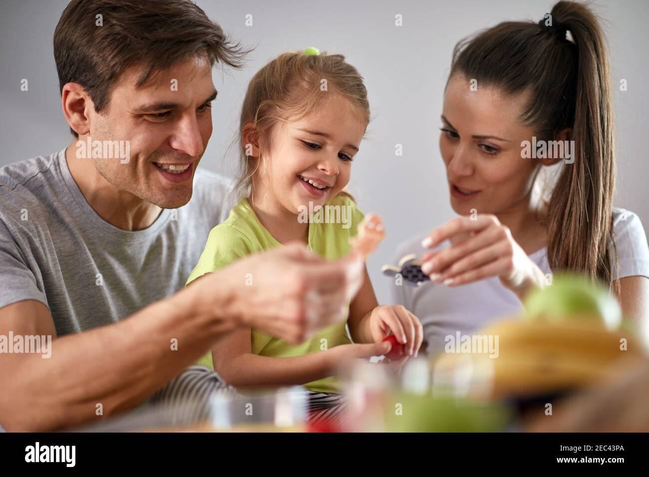 Joyful parents playing together with their daughter at home Stock Photo ...