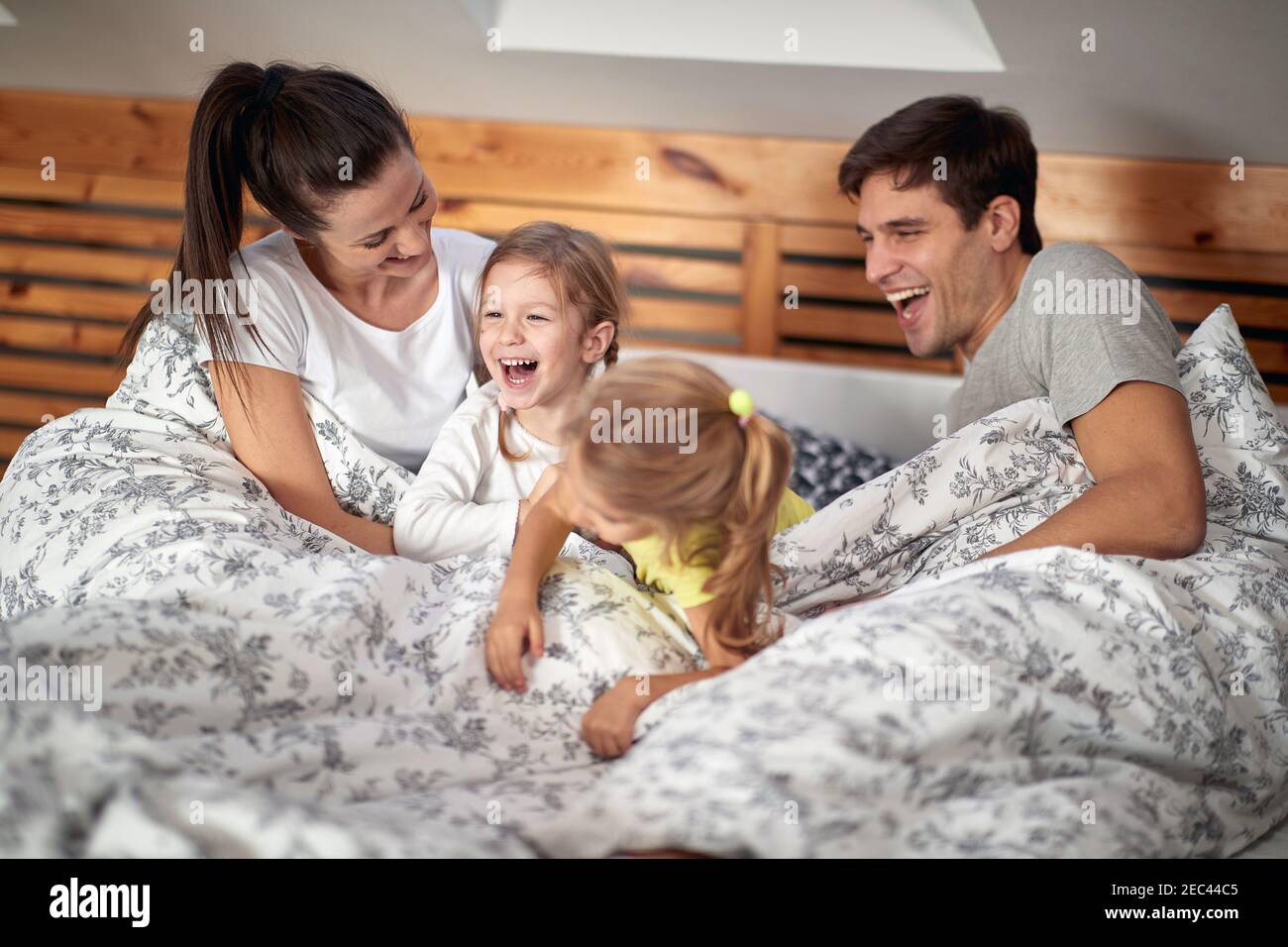 Happy parents cuddling together with kids in the bed Stock Photo - Alamy