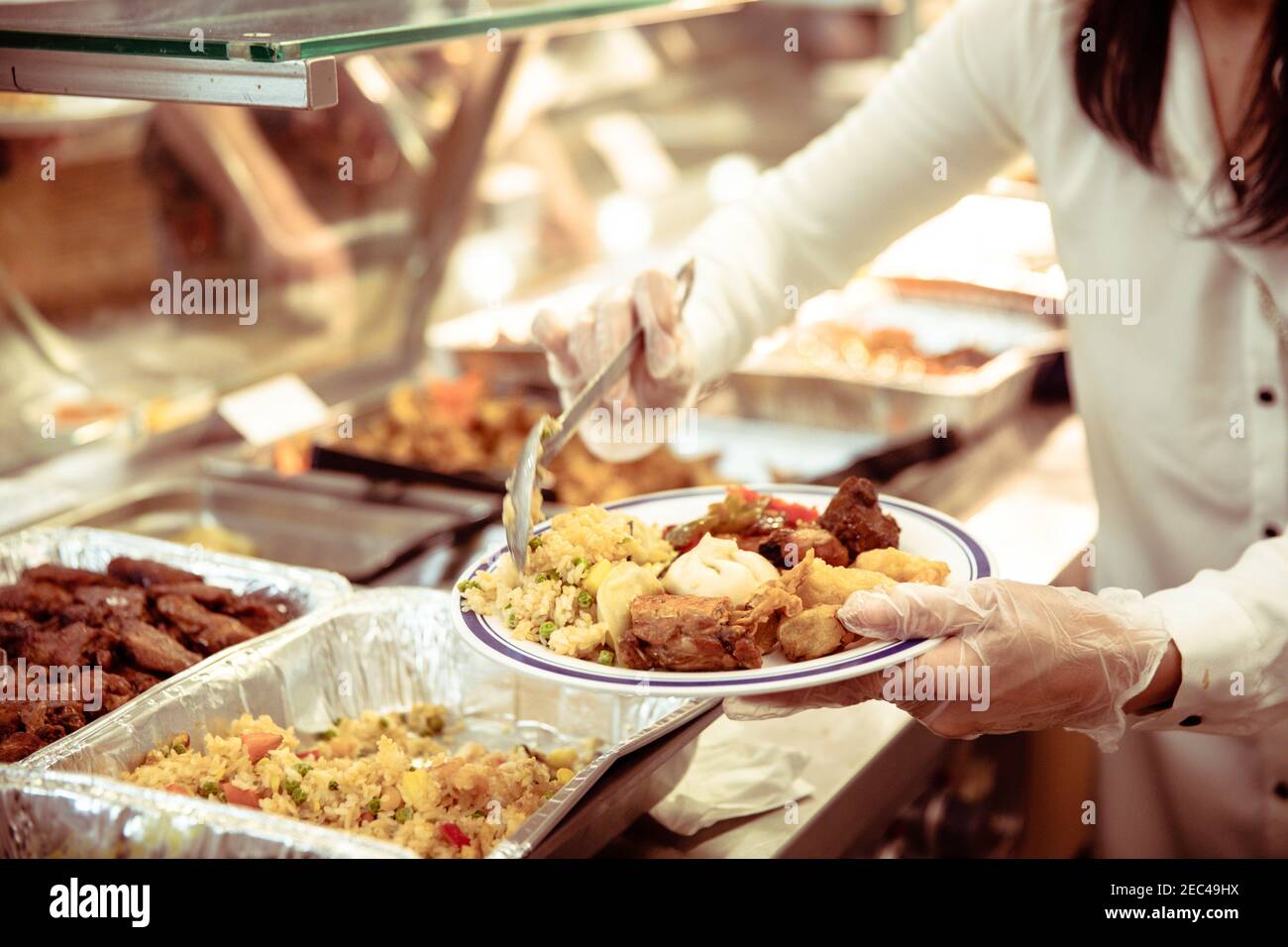 Woman wearing plastic gloves putting food on a plate - celebration and ...