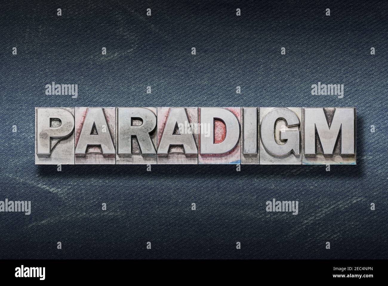 paradigm word made from metallic letterpress on dark jeans background ...
