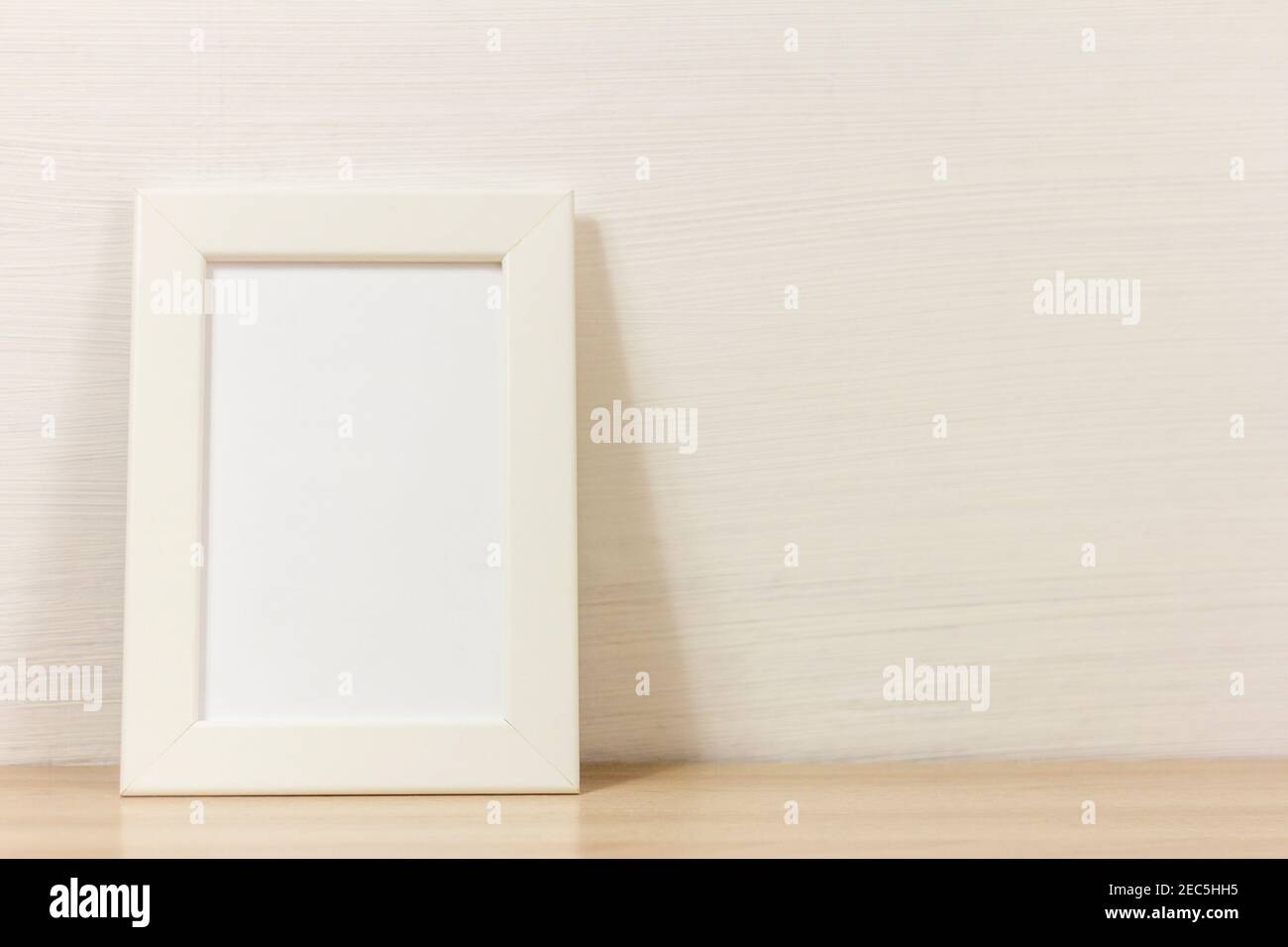 An empty wooden photo frame on a table or shelf with a copy of the ...