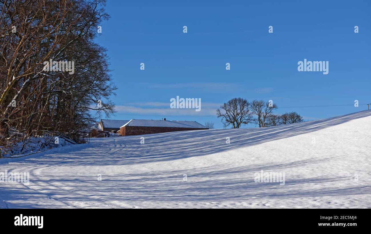 A Farm and its snow covered Stone outbuildings above a sloping field ...