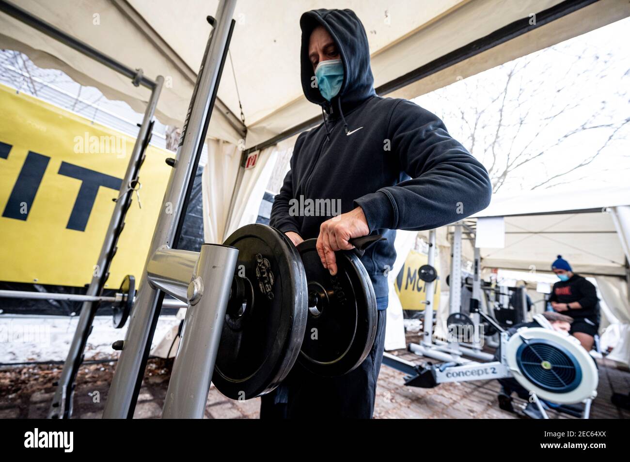 Berlin, Germany. 13th Feb, 2021. A man lifts weights from their holders ...