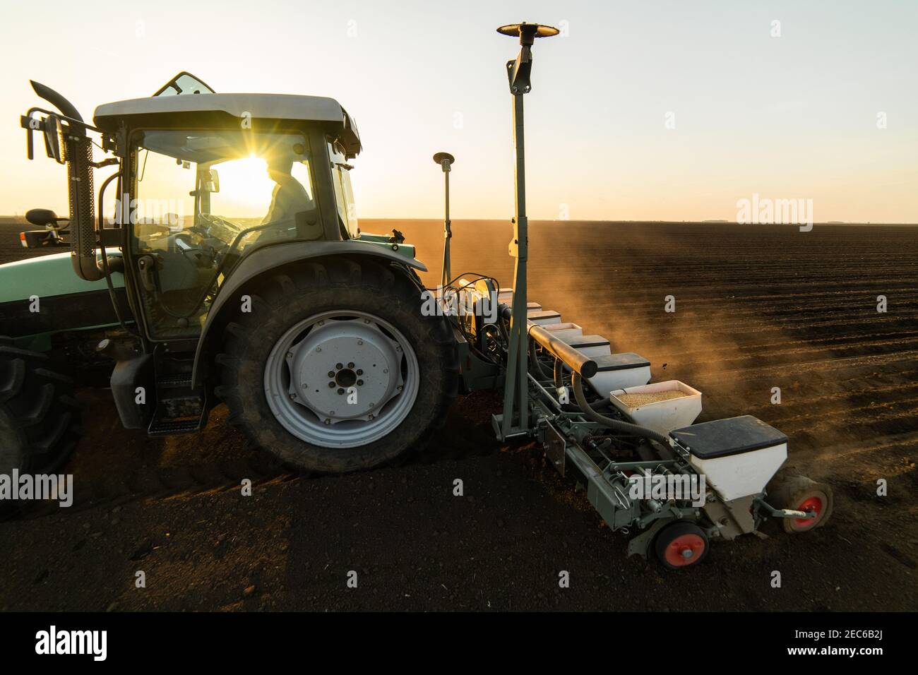 Farmer with tractor seeding - sowing crops at agricultural field ...