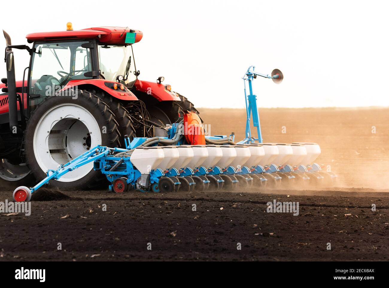 Farmer with tractor seeding - sowing crops at agricultural field ...