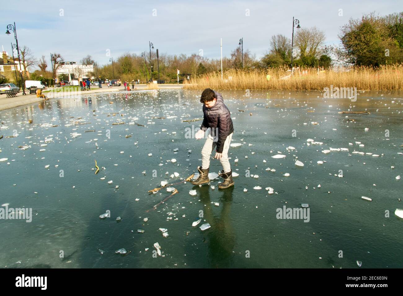 A teenaged boy walks on a frozen pond in risky and dangerous behaviour ...