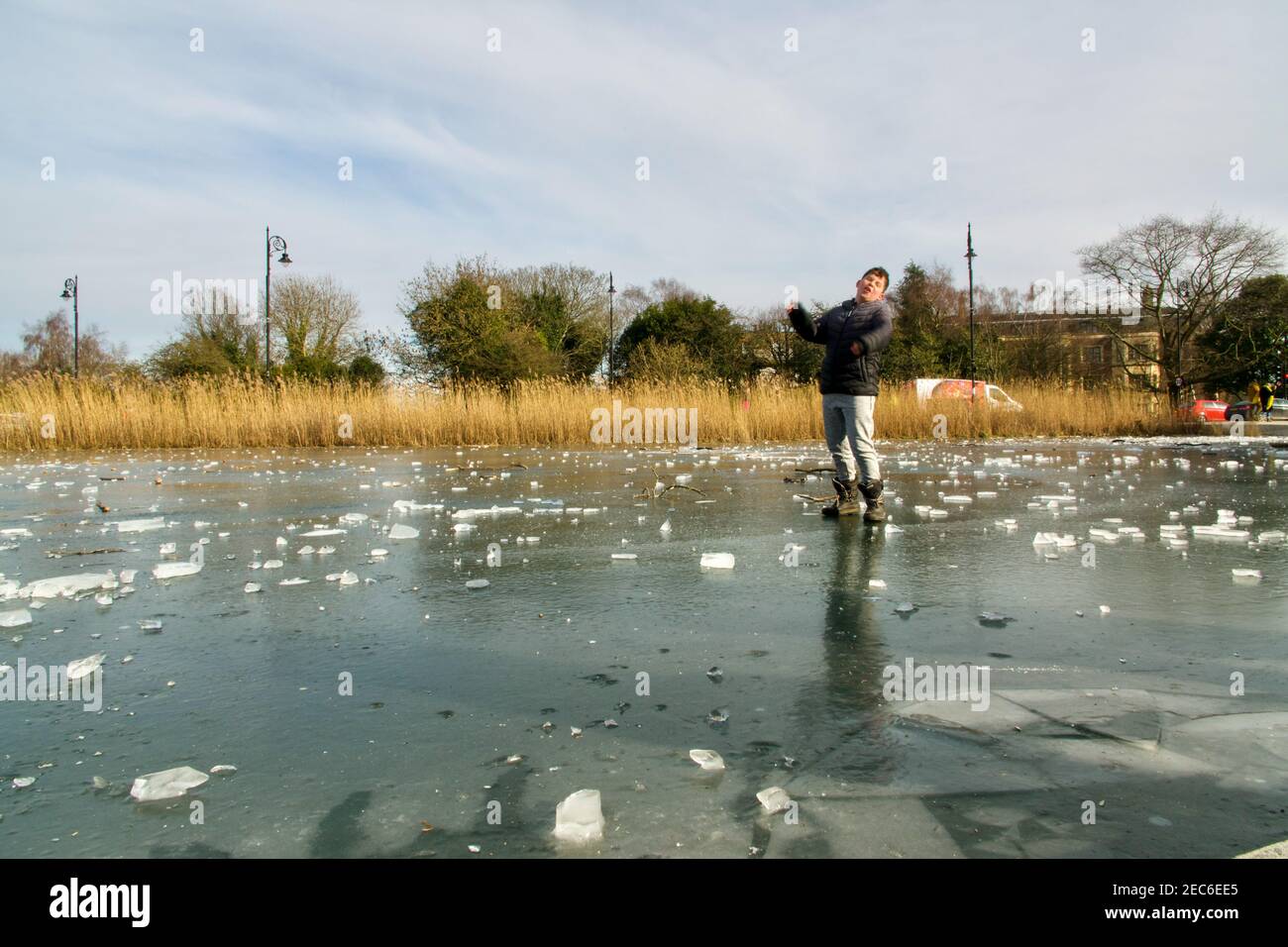 A teenaged boy walks on a frozen pond in risky and dangerous behaviour ...