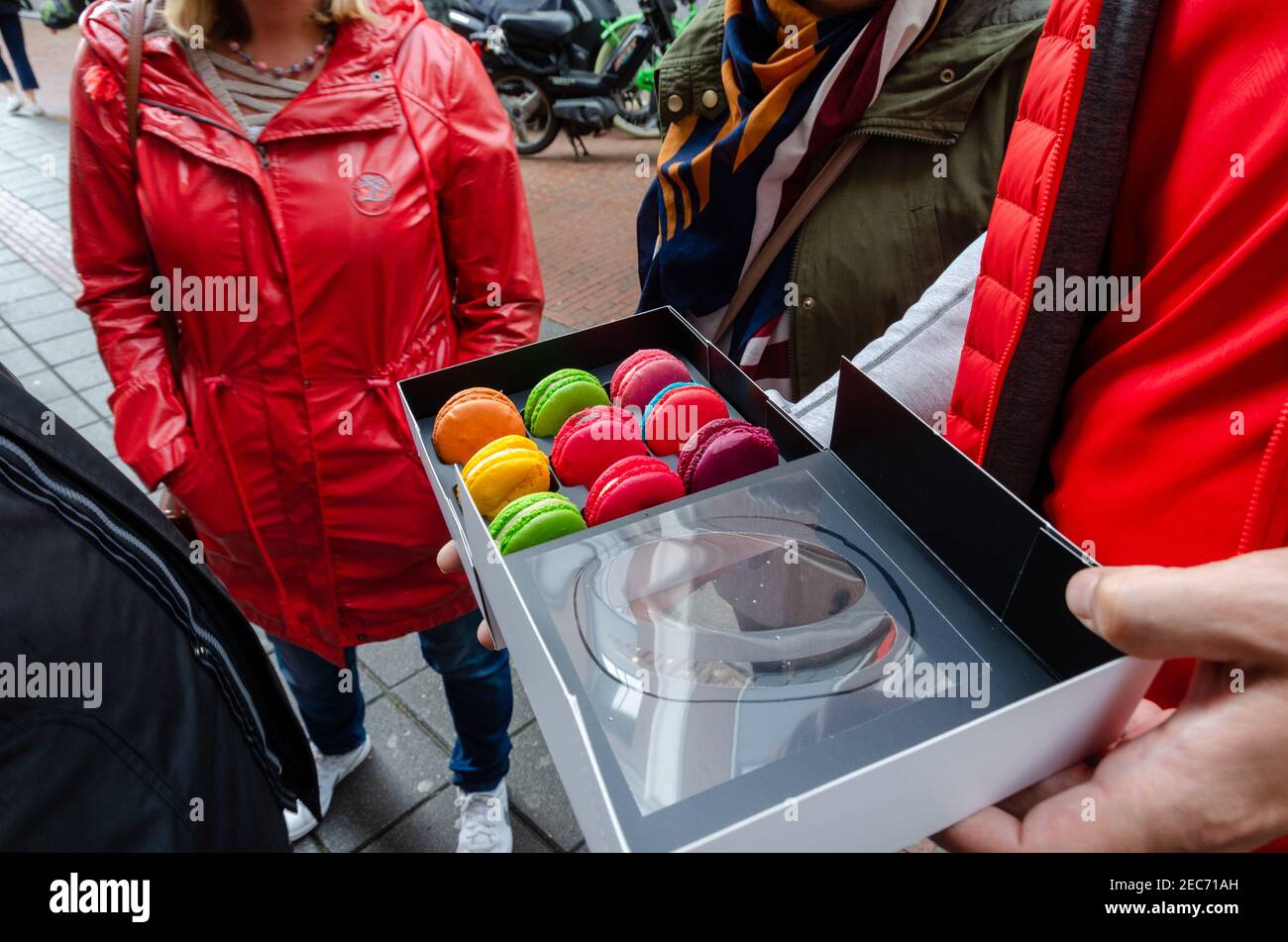 Group of people enjoying a box of french macarons dessert. Friends ...