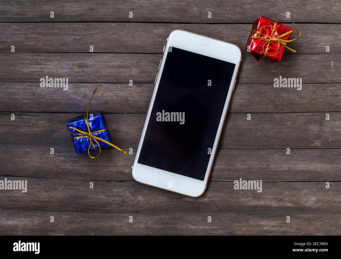 White smartphone with blue and red gifts. Gadget on rustic wooden table ...