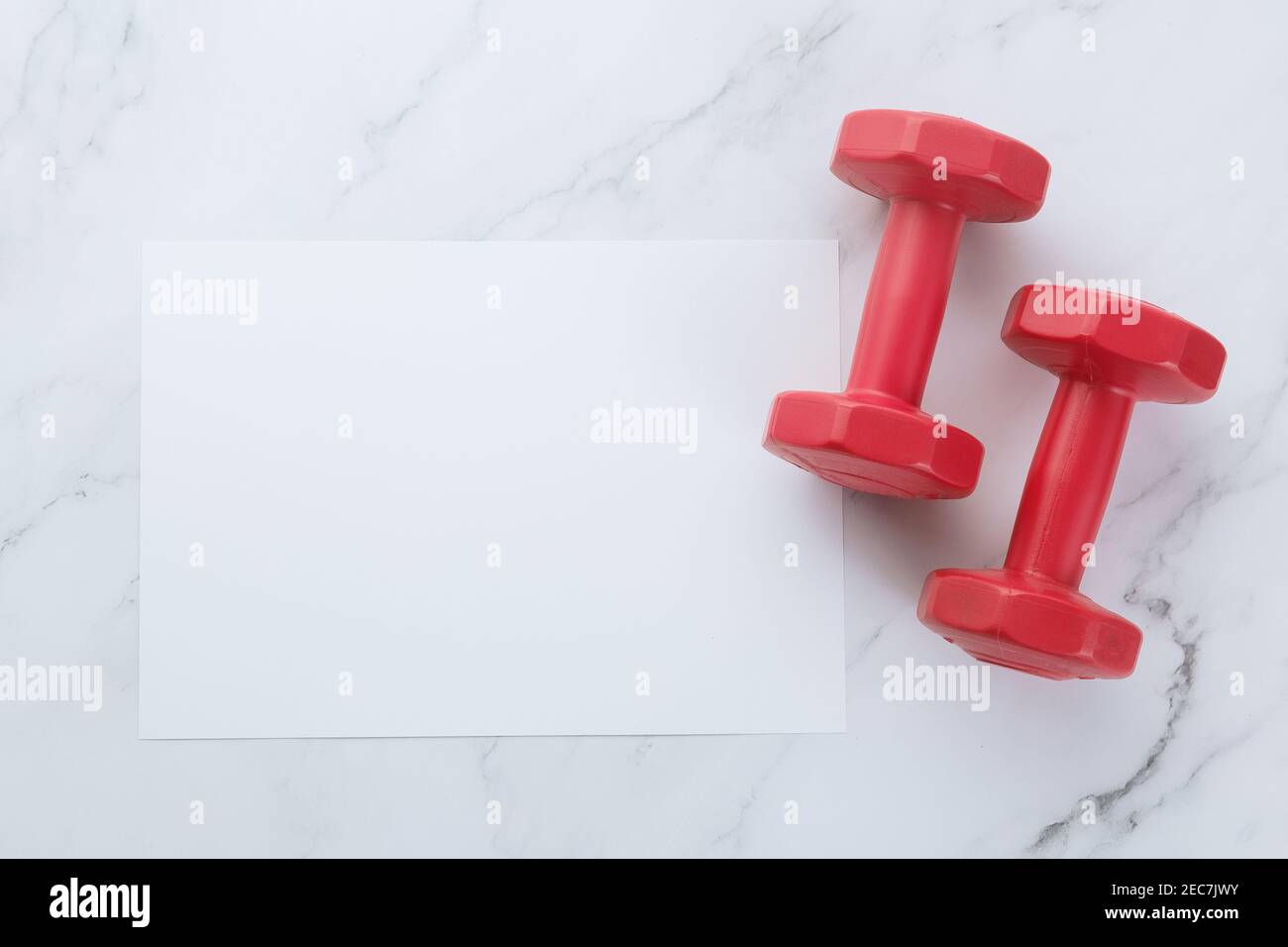 Blank white paper note and dumbells on white marble background. Sport ...