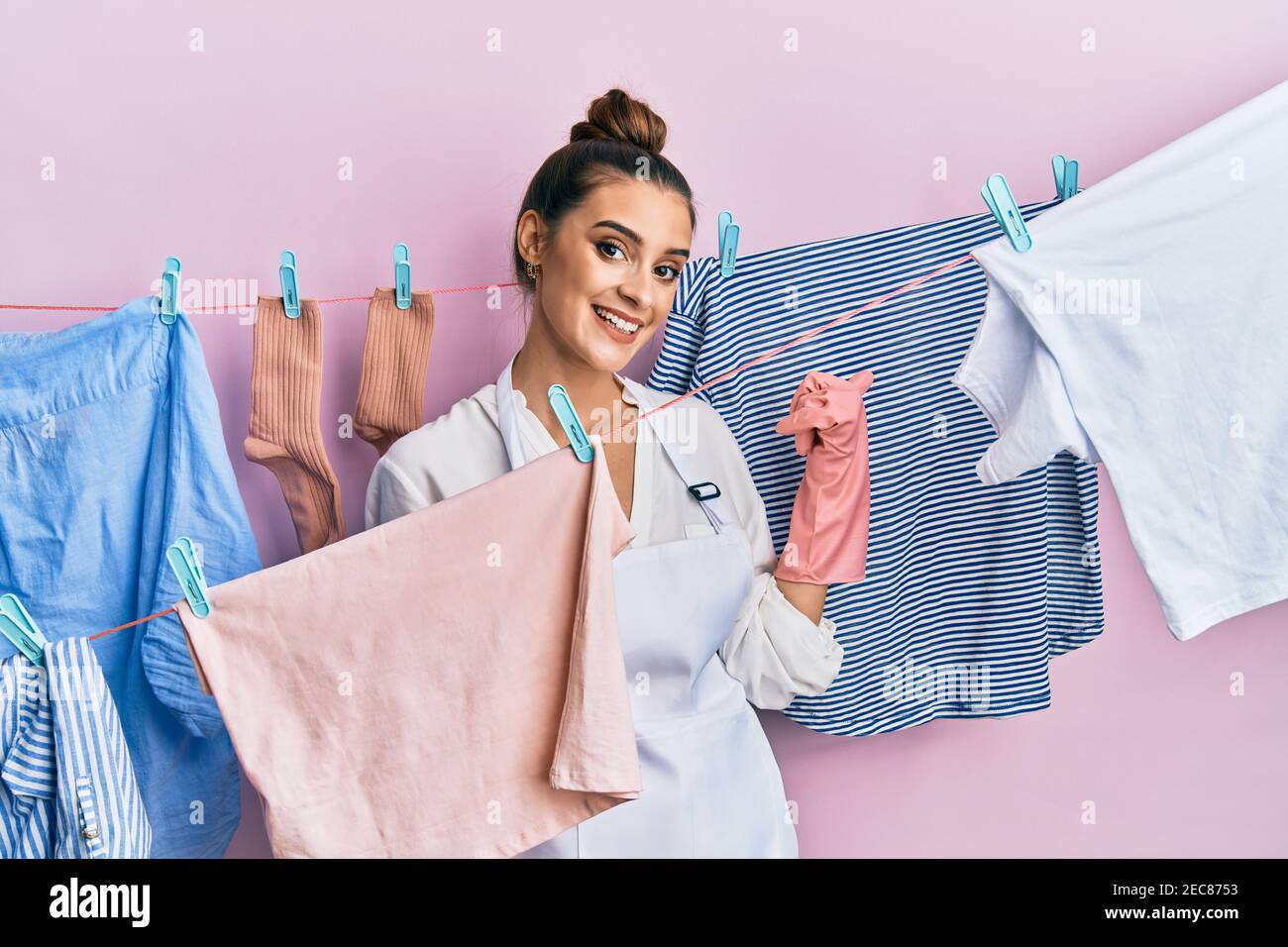 Beautiful brunette young woman washing clothes at clothesline smiling ...