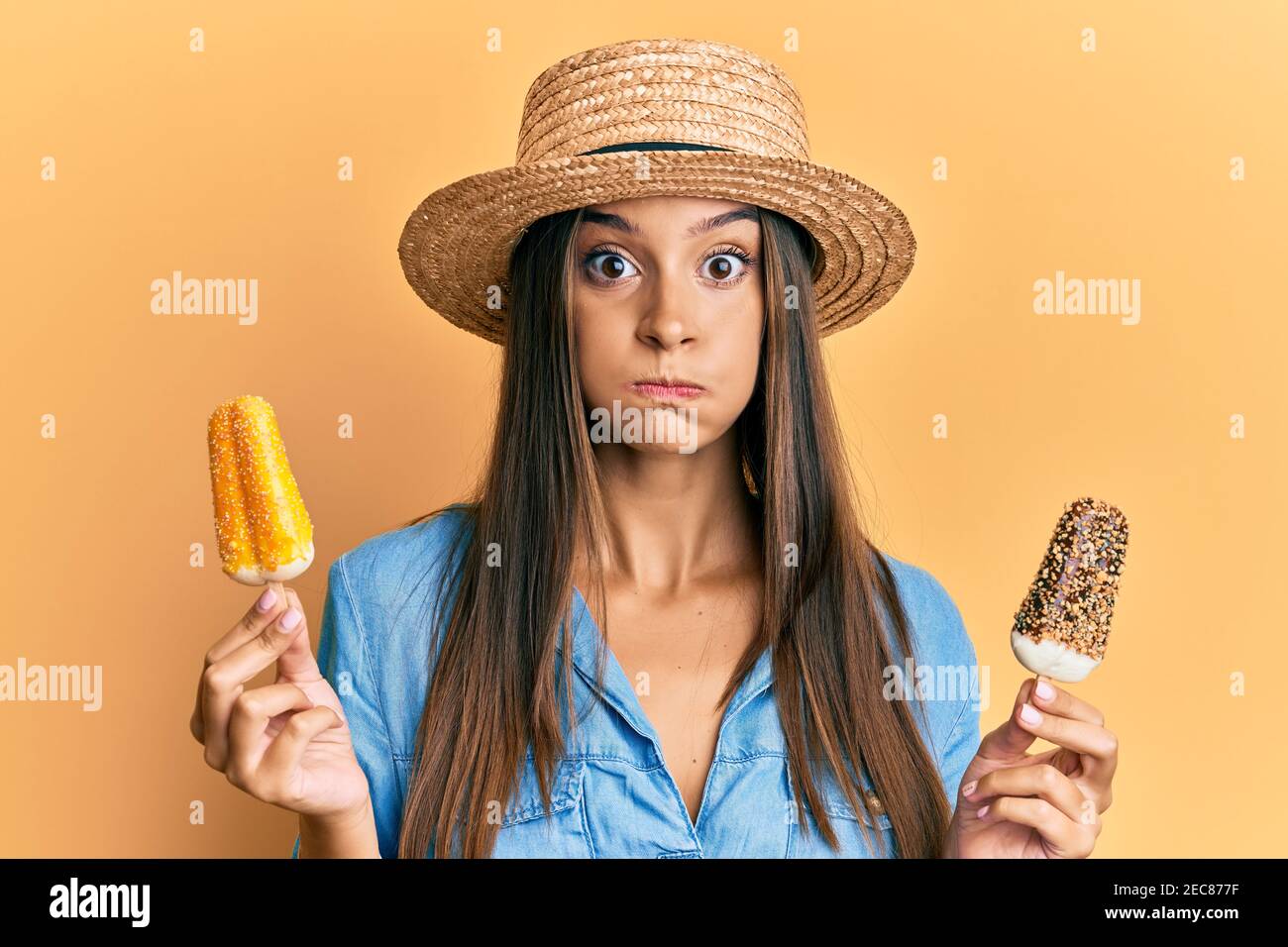 Young hispanic woman wearing summer style holding ice cream puffing ...