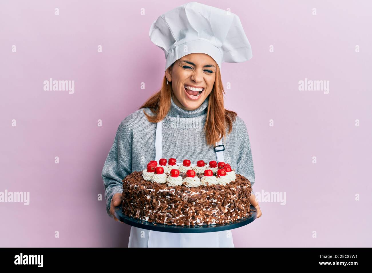 Hispanic young chef woman holding chocolate cake smiling and laughing ...