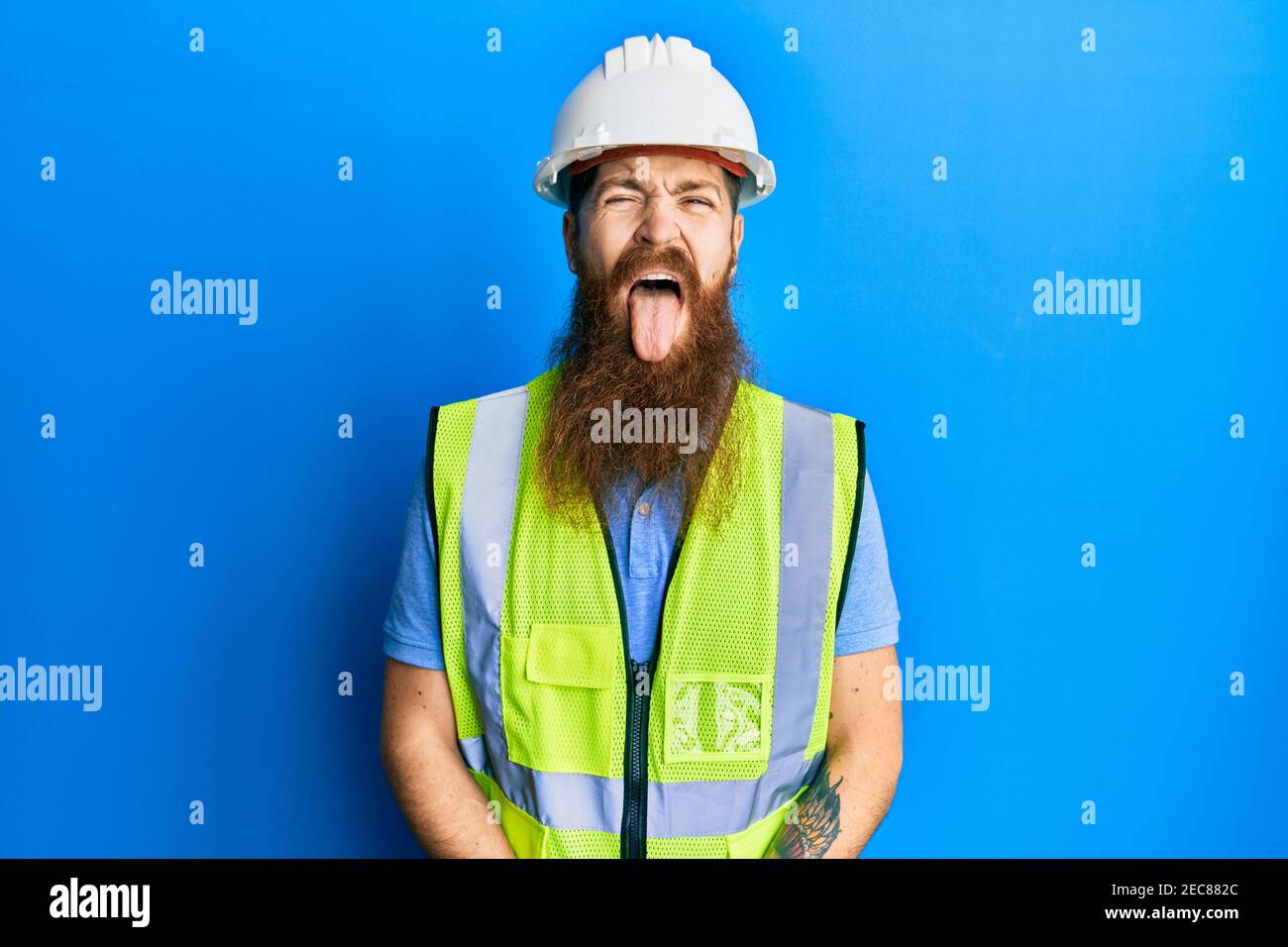 Redhead man with long beard wearing safety helmet and reflective jacket ...