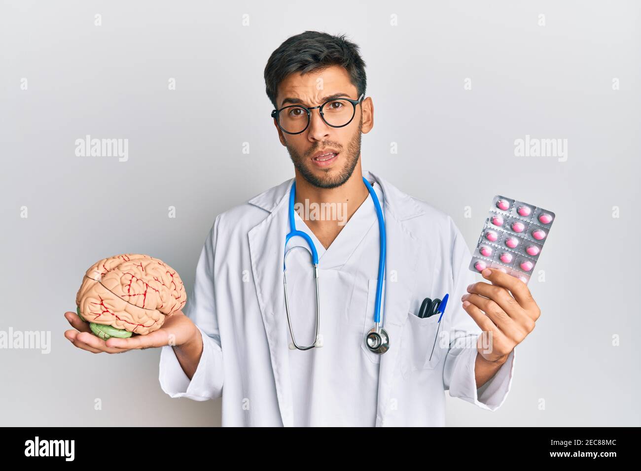 Young handsome man holding brain and pills as mental health concept in ...