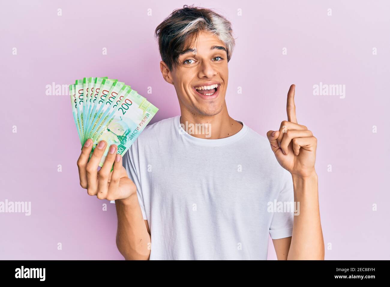 Young hispanic man holding russian 200 ruble banknotes smiling with an ...
