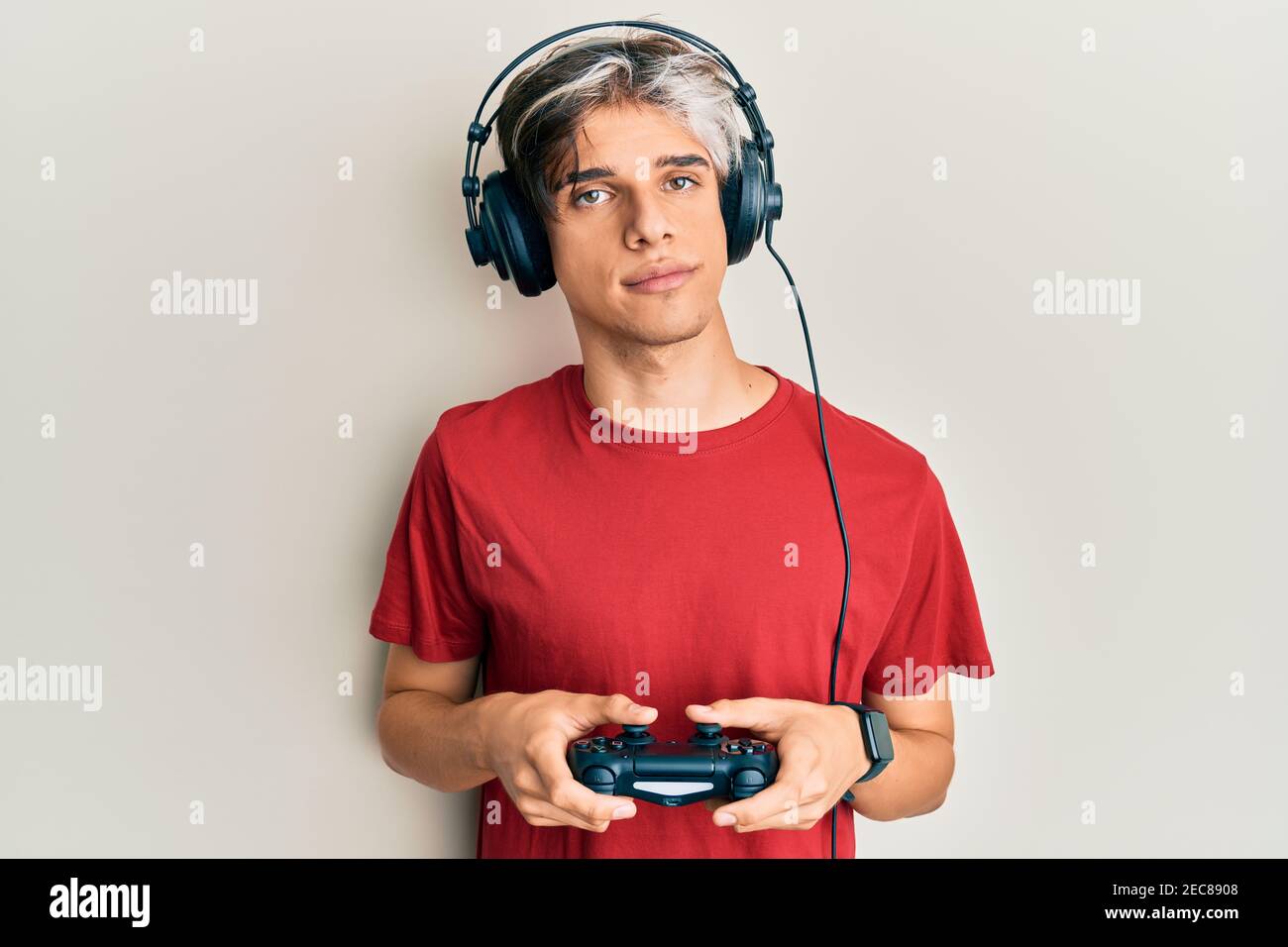 Young hispanic man playing video game holding controller relaxed with ...