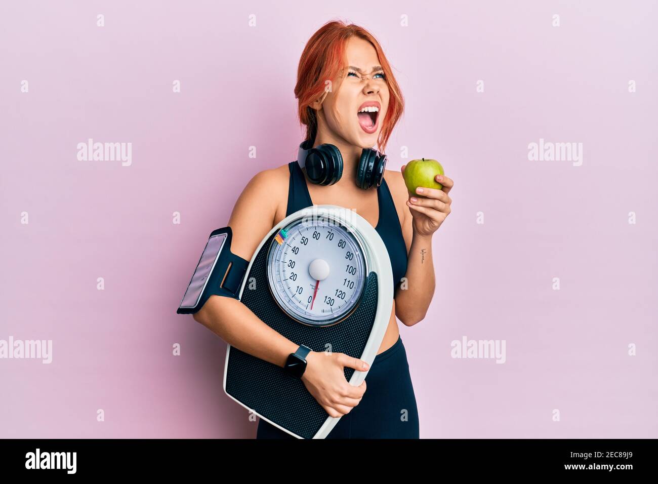 Young beautiful redhead woman holding weight machine to balance weight ...