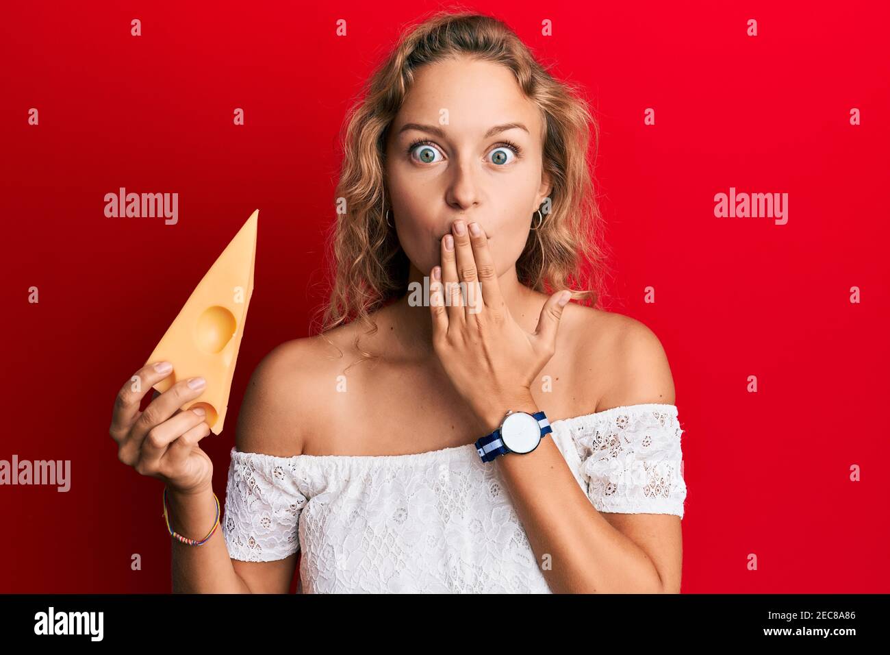 Beautiful caucasian woman holding a piece of emmental cheese covering ...
