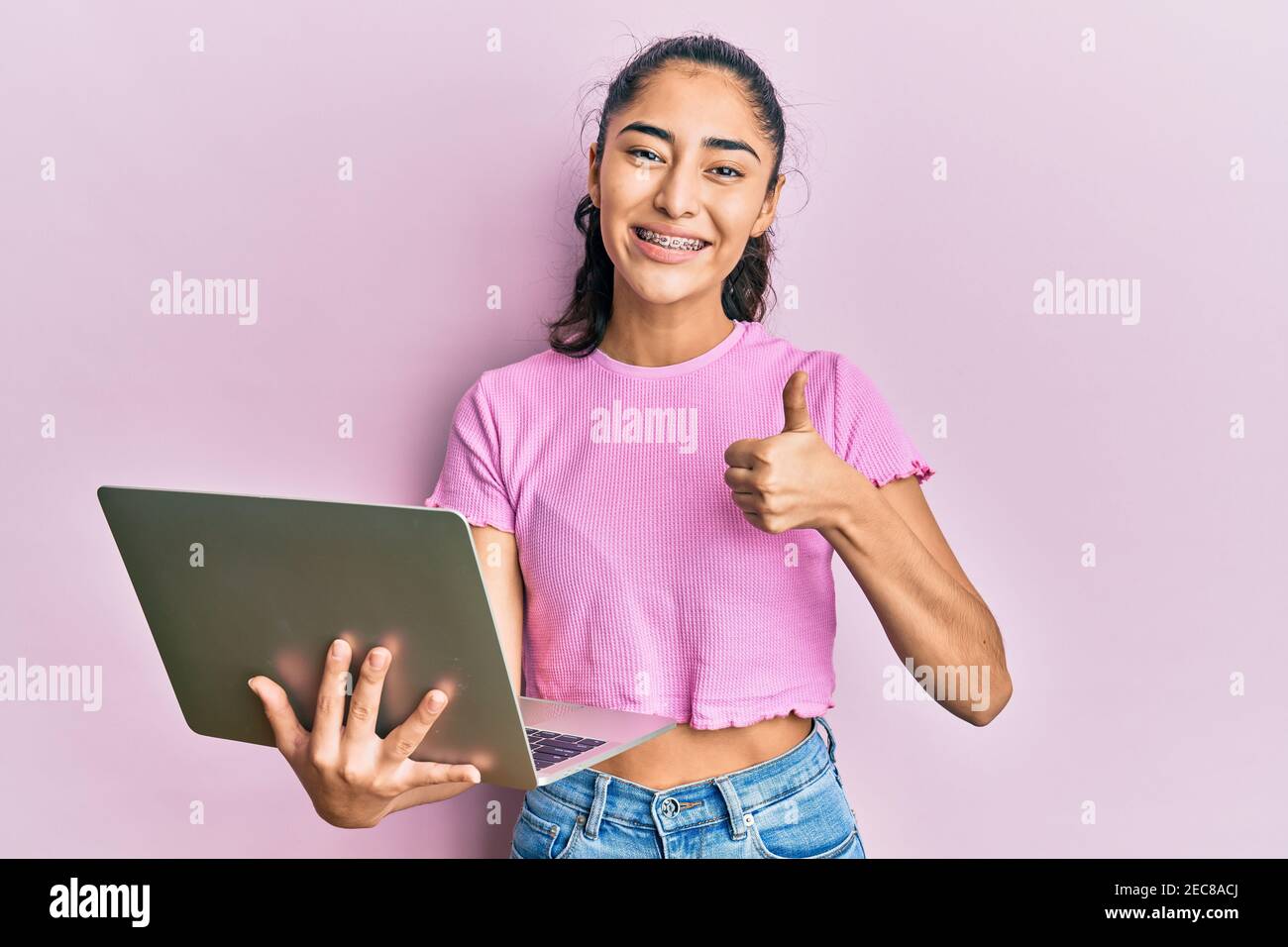 Hispanic teenager girl with dental braces holding and using computer ...