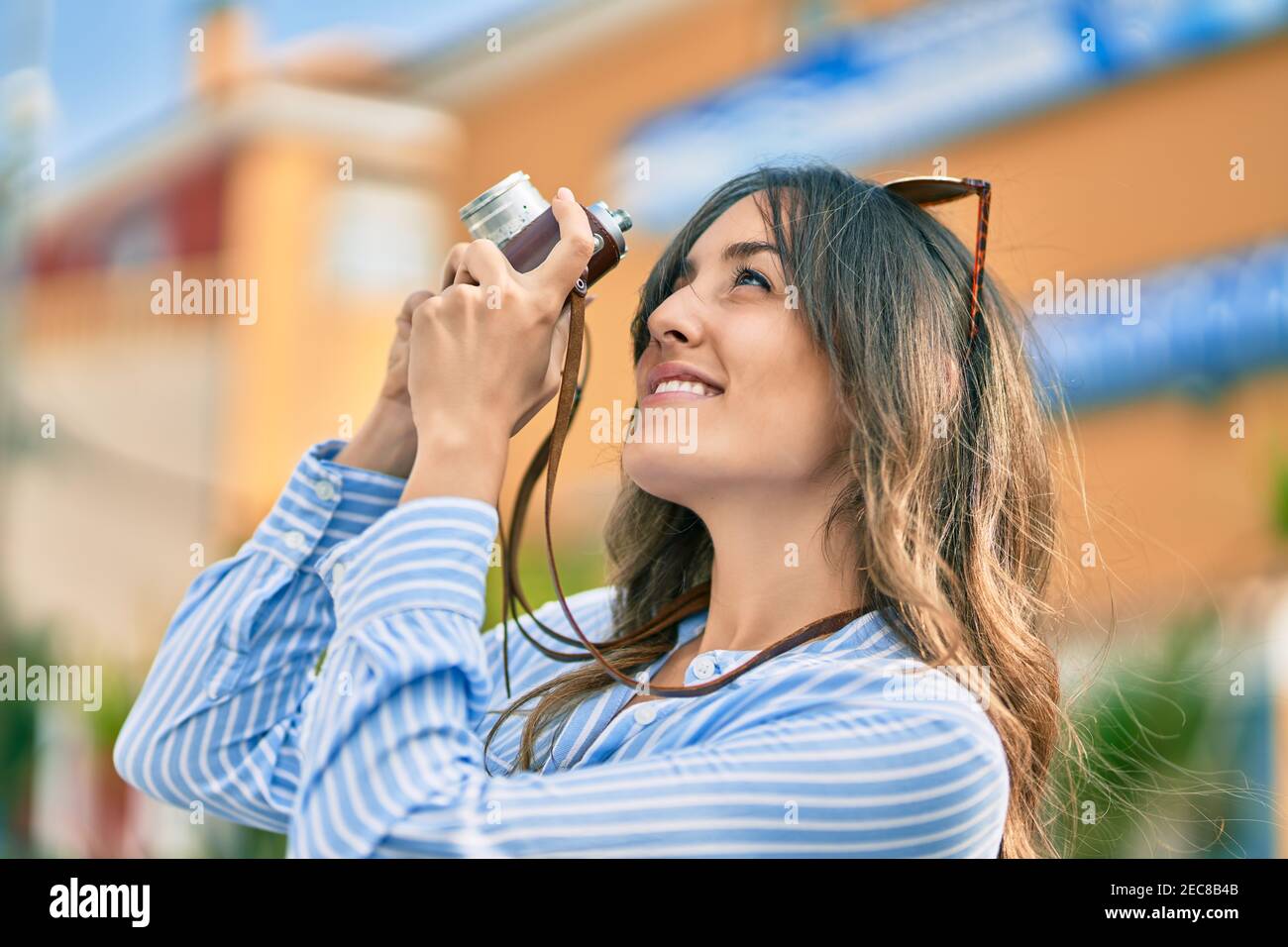 Young hispanic tourist woman smiling happy using vintage camera at the city Stock Photo - Alamy