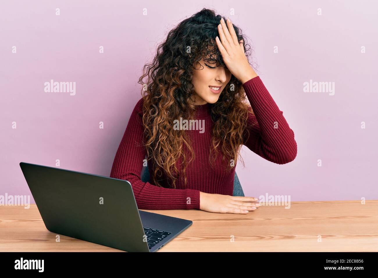 Young hispanic girl working using computer laptop surprised with hand ...