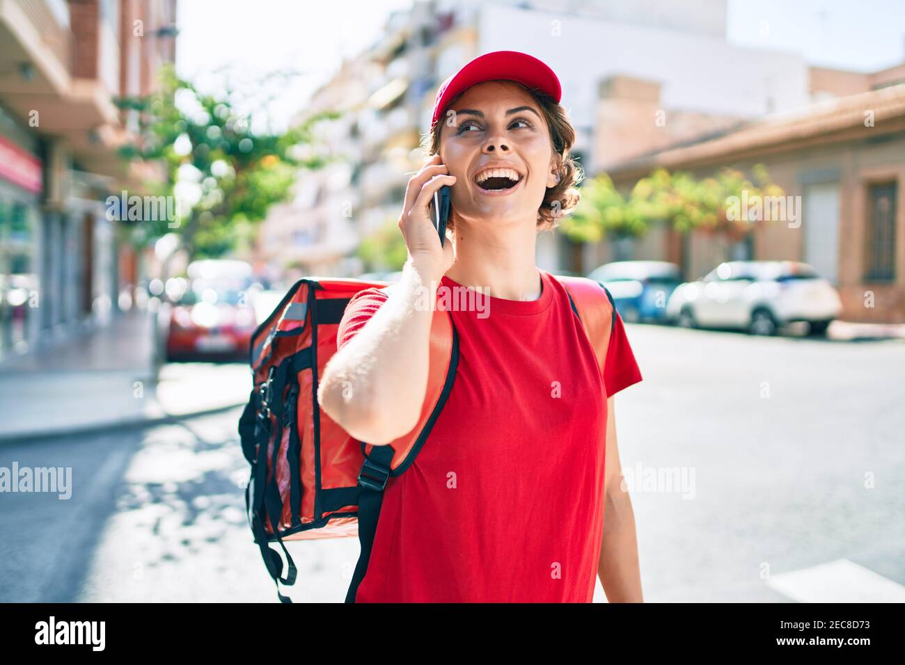Delivery business worker woman wearing uniform and delivery bag smiling happy speaking on the ...