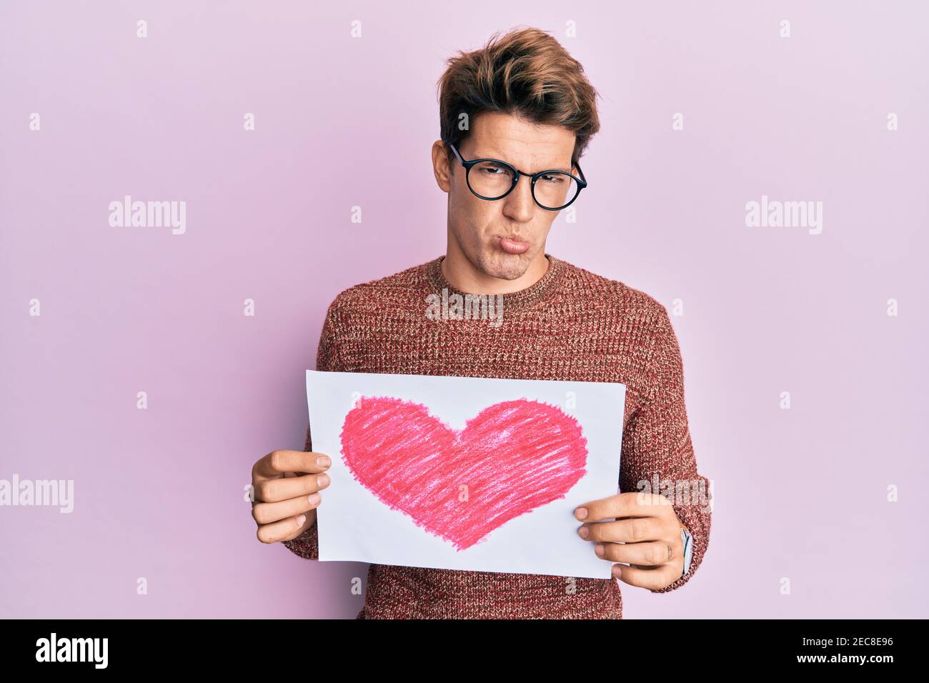 Handsome caucasian man holding heart draw depressed and worry for ...