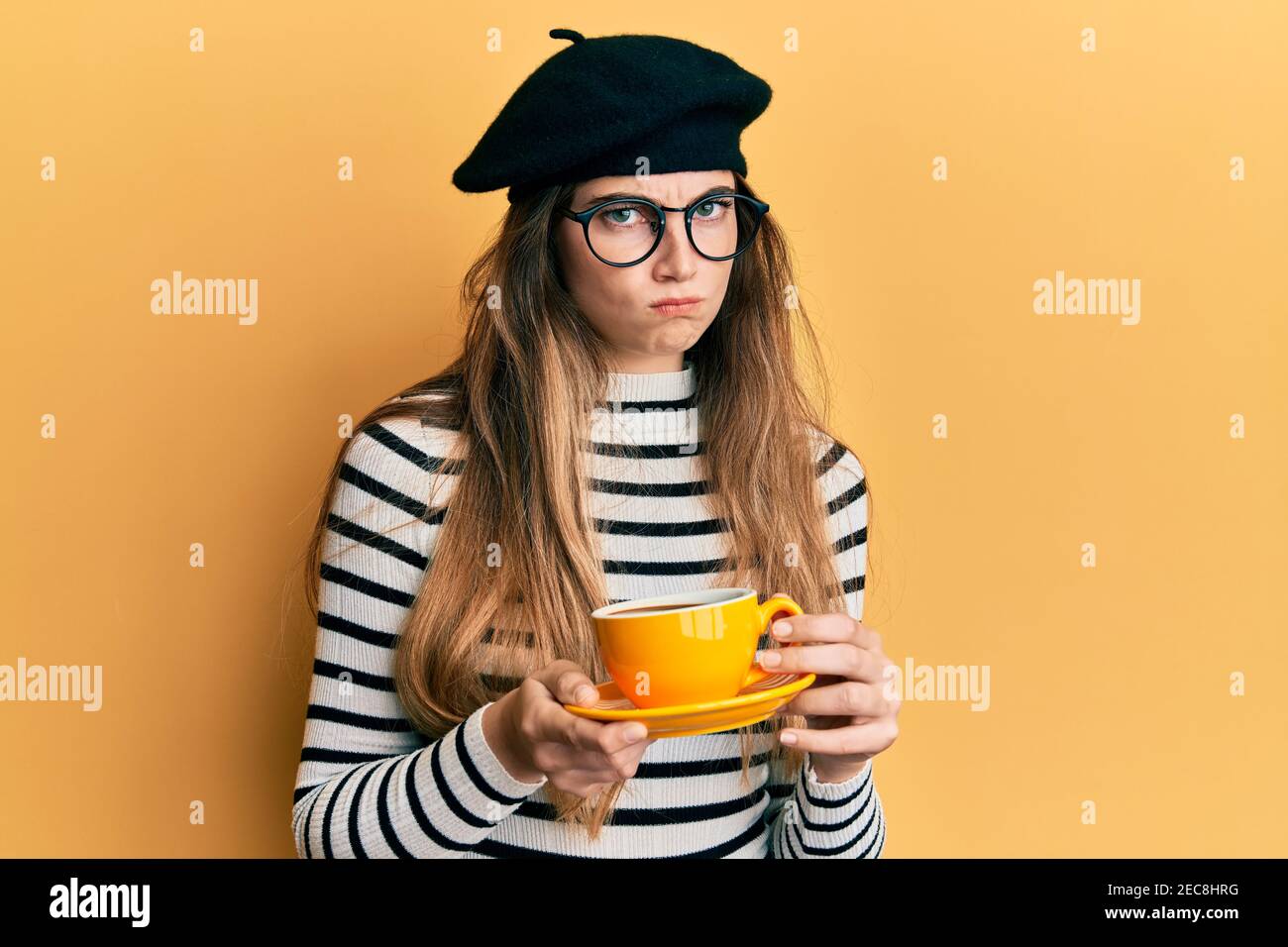 Young caucasian woman wearing french style drinking a cup of coffee ...