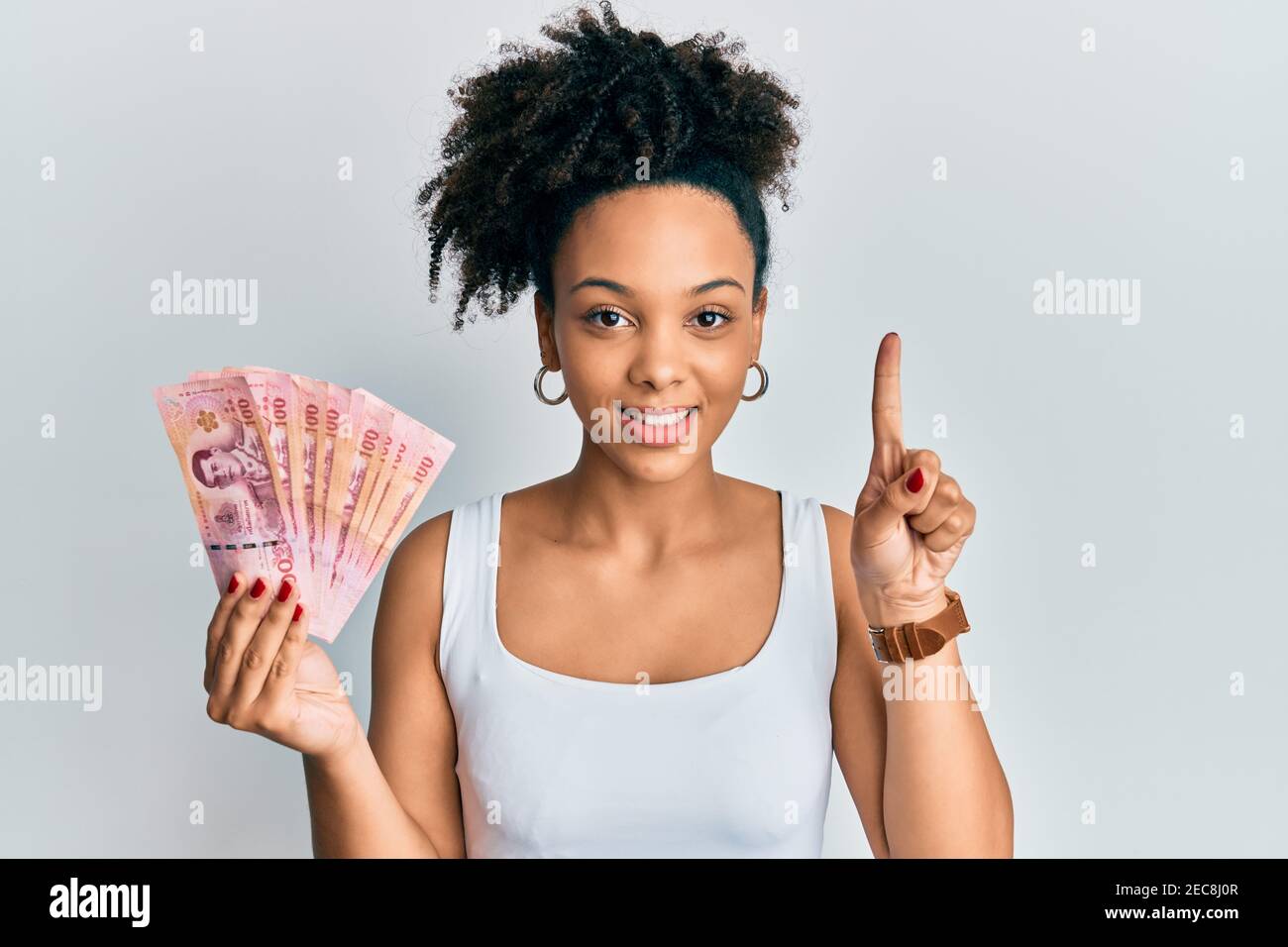 Young african american girl holding thai baht banknotes smiling with an ...