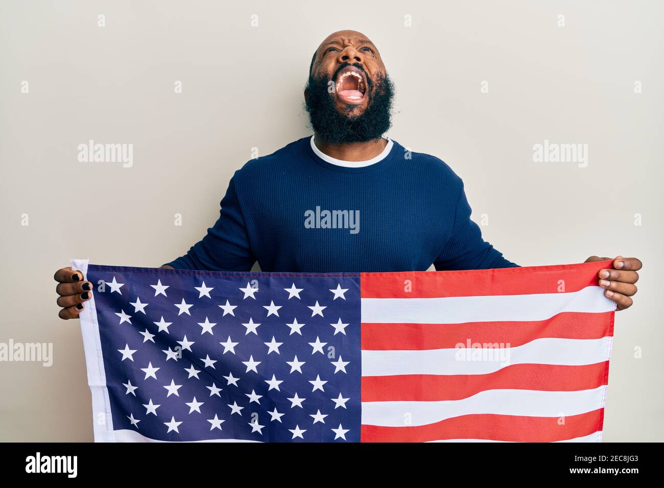 Young african american man holding united states flag angry and mad ...