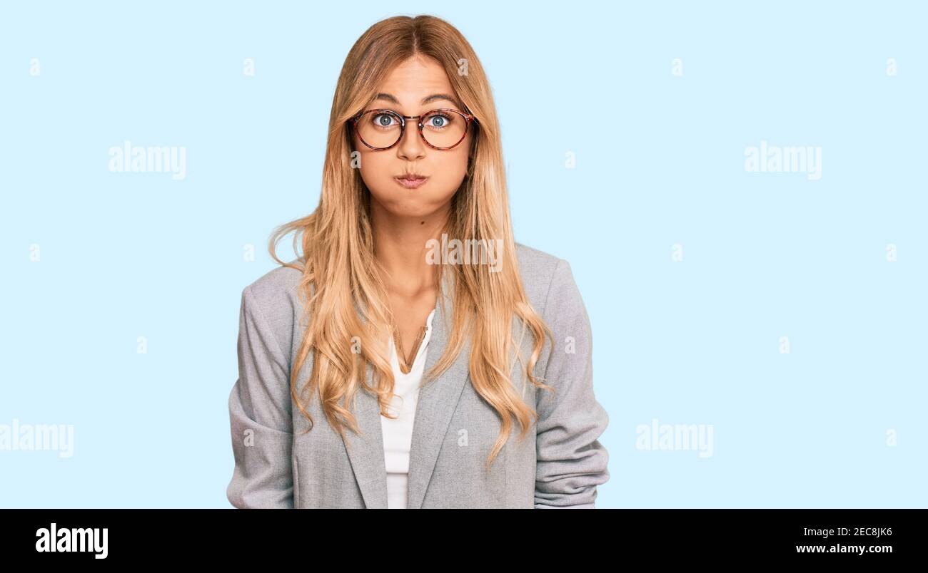 Beautiful blonde young woman wearing business clothes puffing cheeks ...