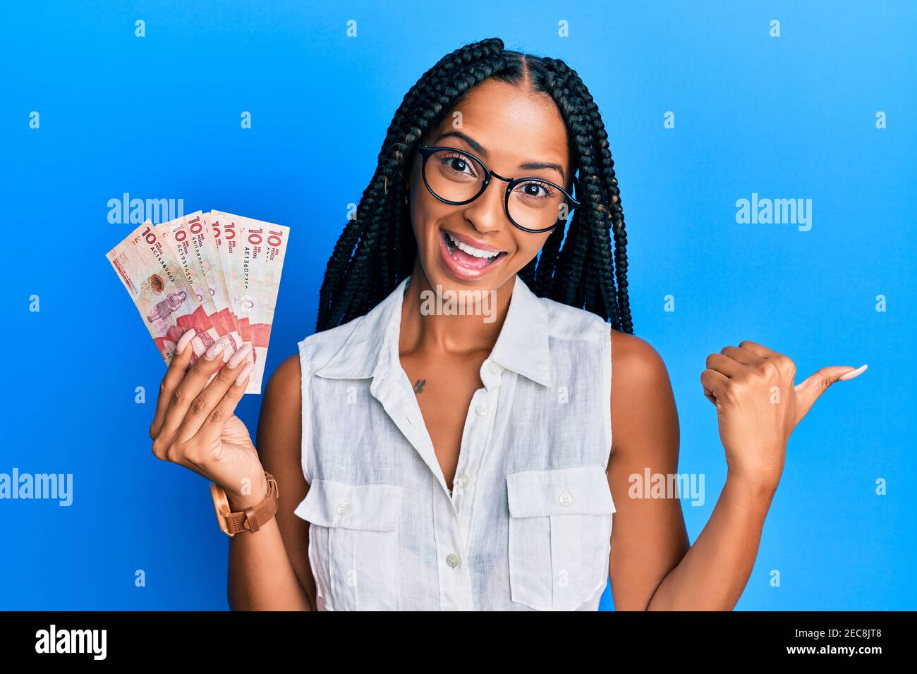Beautiful hispanic woman holding 10 colombian pesos banknotes pointing ...