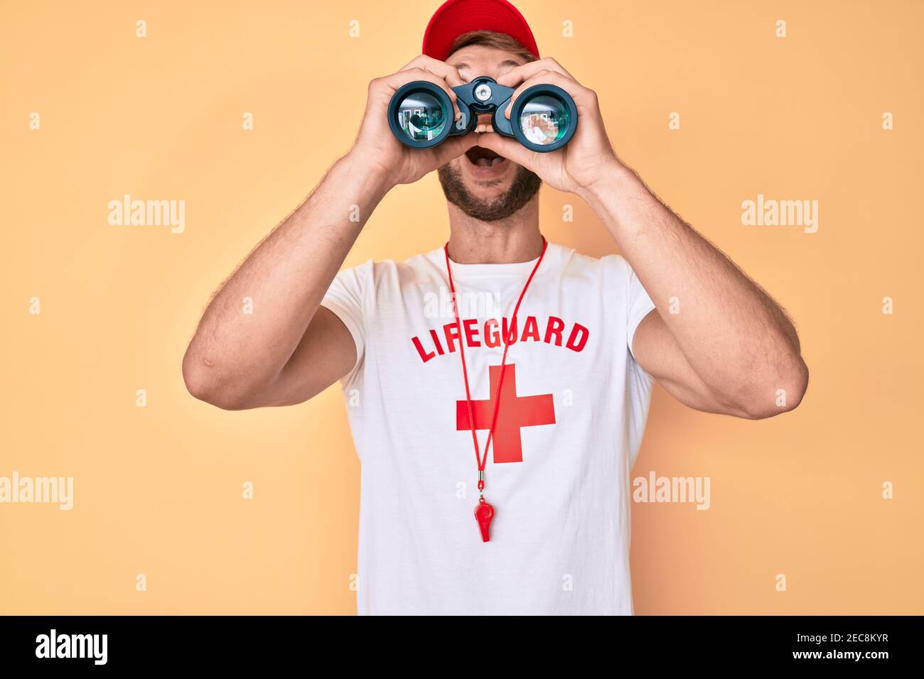 Young caucasian man wearing lifeguard t-shirt using binoculars angry ...