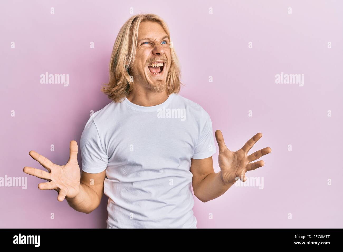 Caucasian young man with long hair wearing casual white t shirt crazy ...