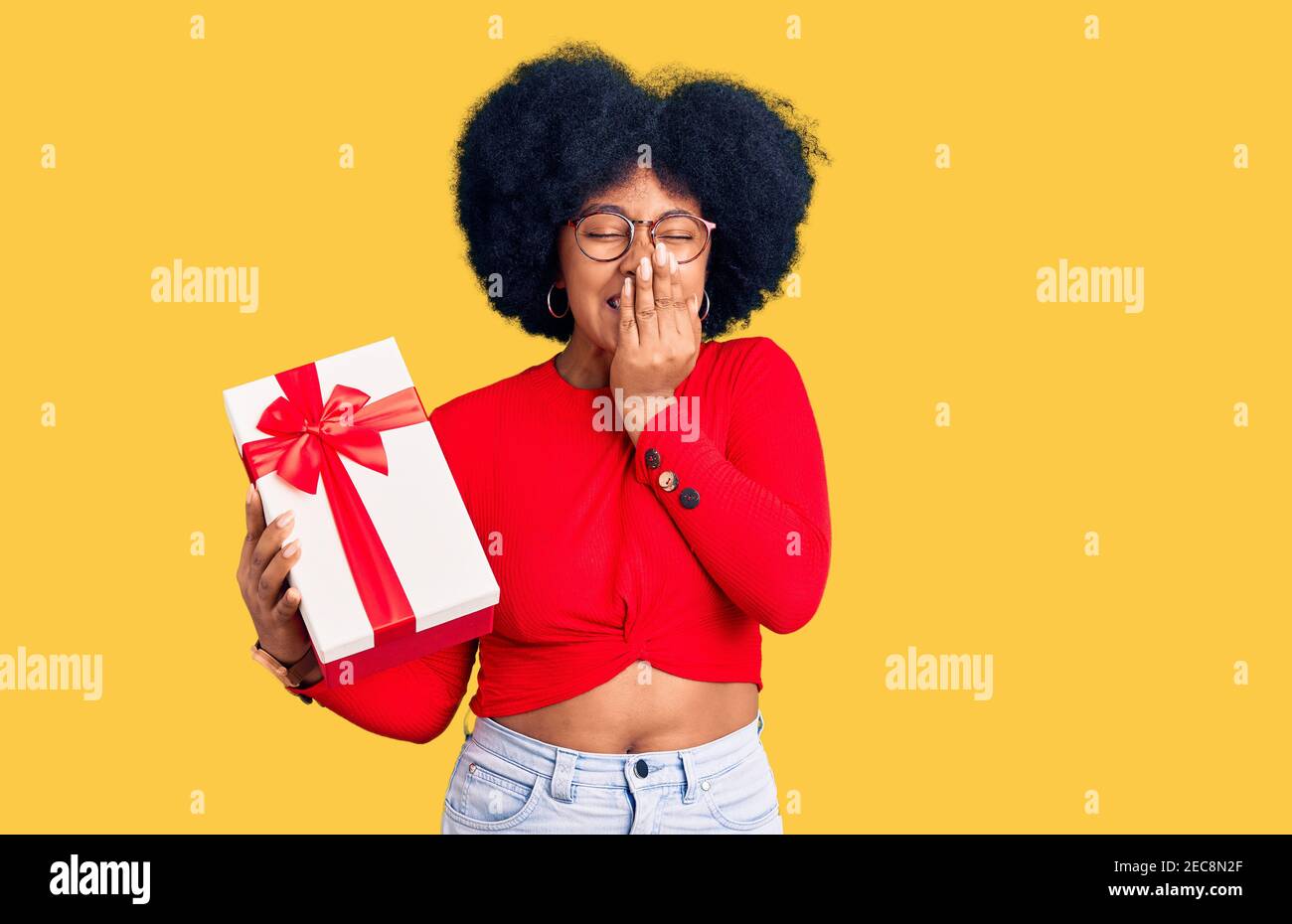 Young african american girl holding gift laughing and embarrassed ...