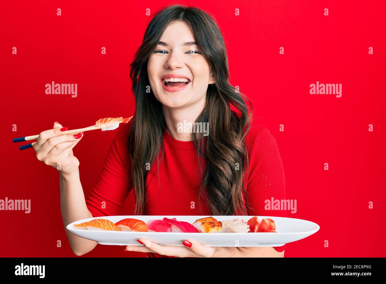 Young beautiful caucasian girl eating sushi using chopsticks smiling ...