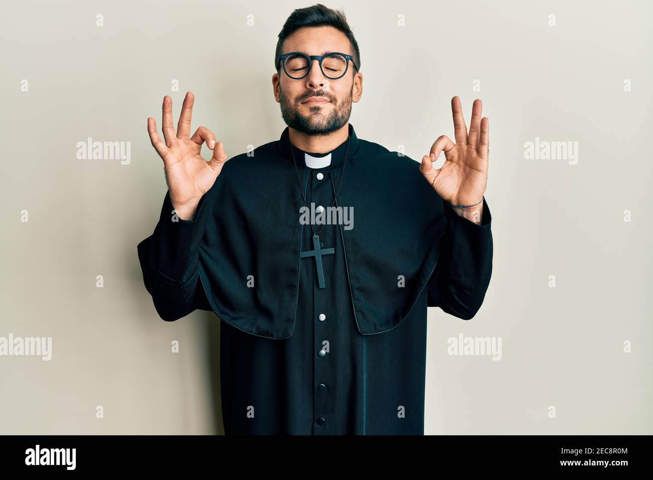 Young hispanic man wearing priest uniform standing over white ...