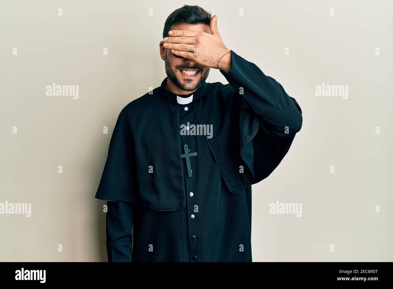 Young hispanic man wearing priest uniform standing over white ...