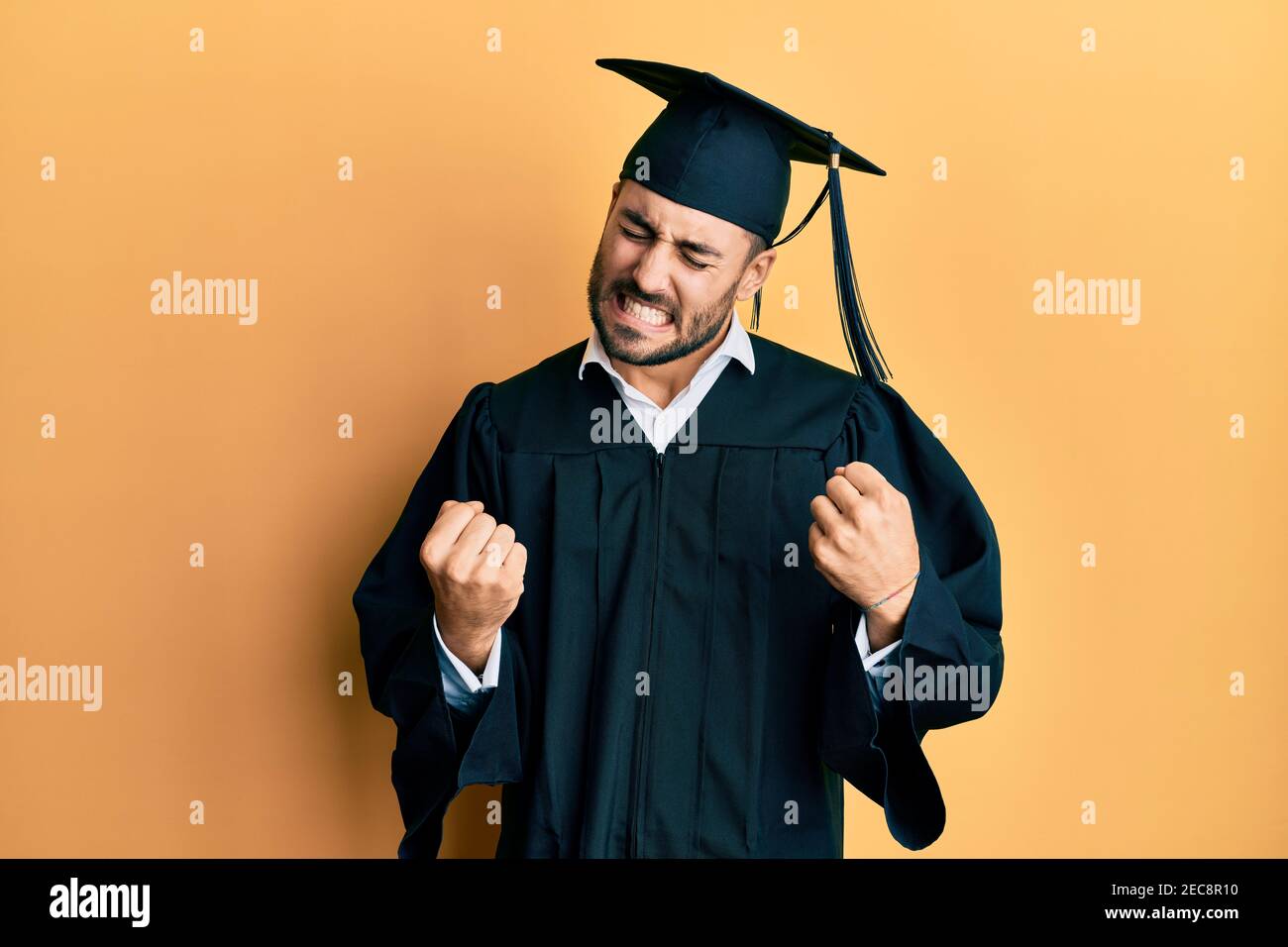 Young hispanic man wearing graduation cap and ceremony robe very happy ...