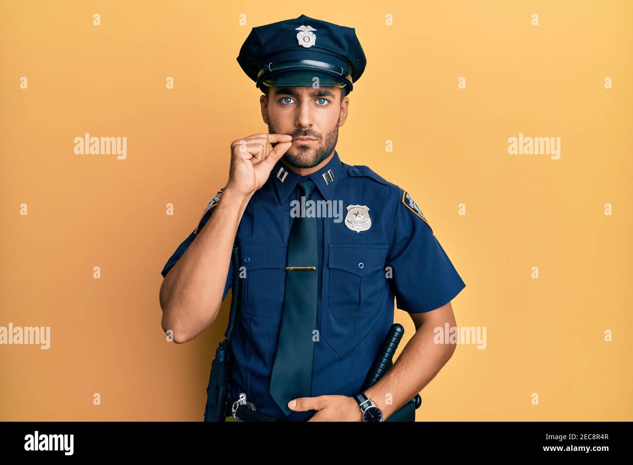 Handsome hispanic man wearing police uniform mouth and lips shut as zip ...