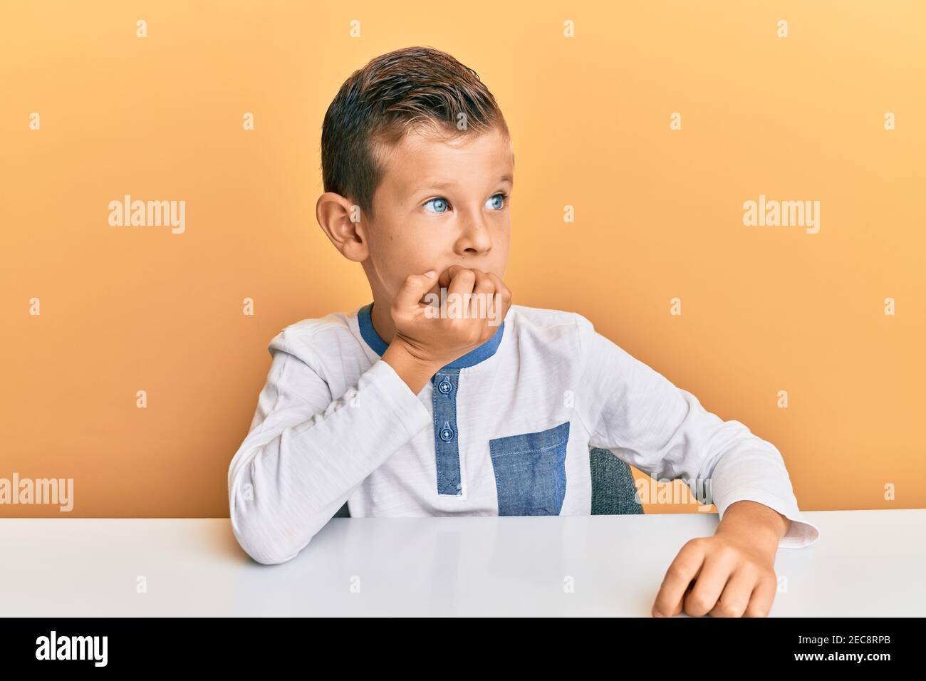 Adorable caucasian kid wearing casual clothes sitting on the table ...
