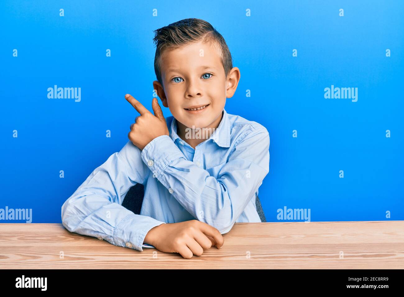 Adorable caucasian kid wearing casual clothes sitting on the table ...