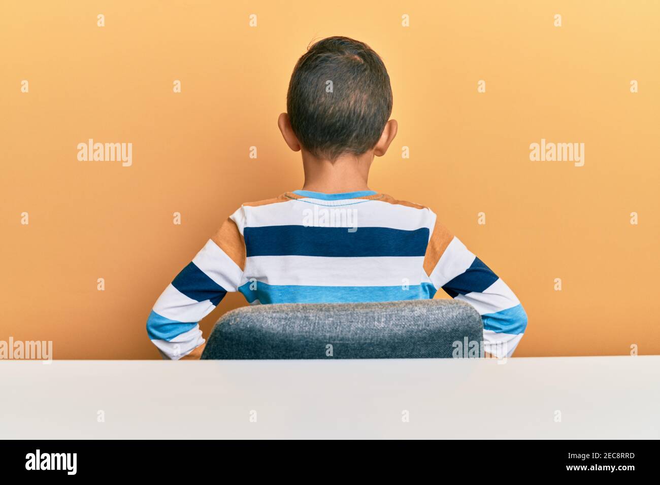 Adorable caucasian kid wearing casual clothes sitting on the table ...