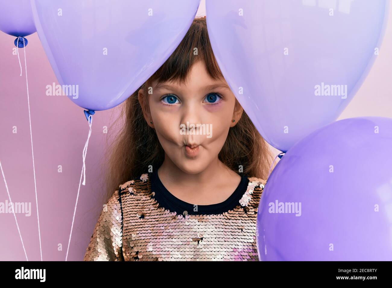Little caucasian girl kid holding balloons puffing cheeks with funny ...