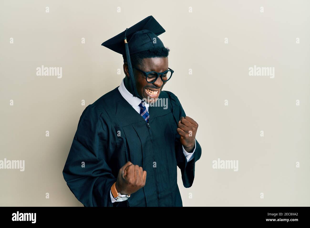 Handsome black man wearing graduation cap and ceremony robe celebrating ...