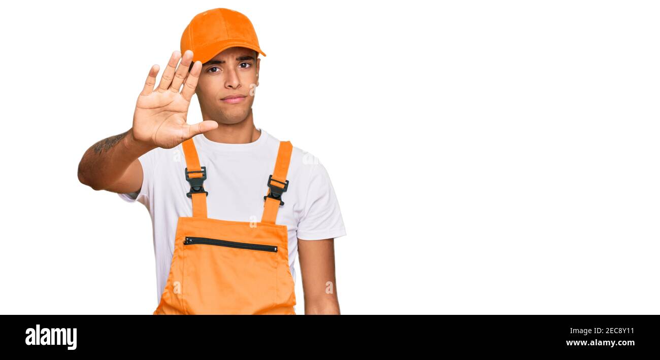Young handsome african american man wearing handyman uniform doing stop ...