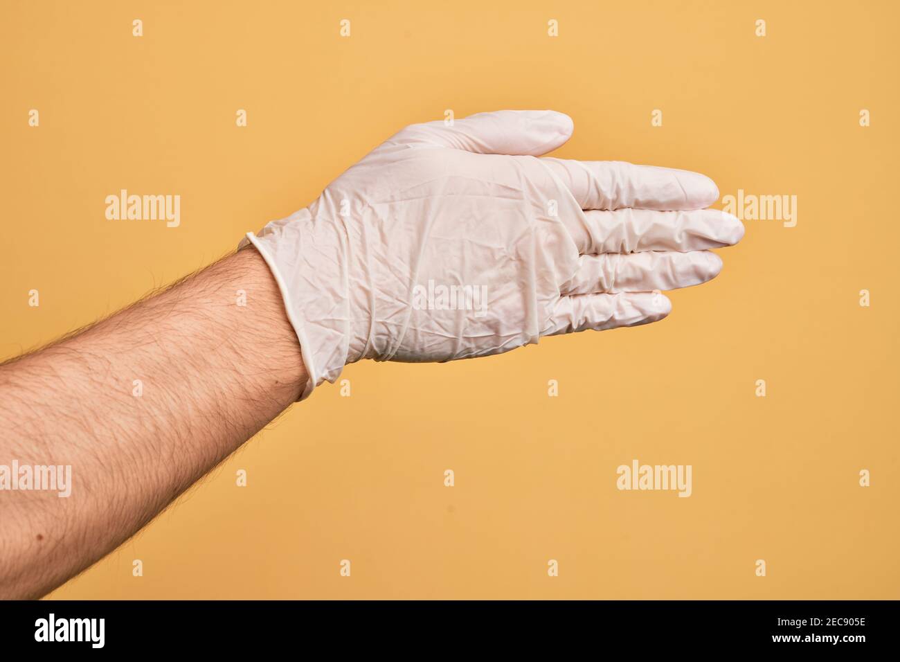 Hand of caucasian young man with medical glove over isolated yellow ...