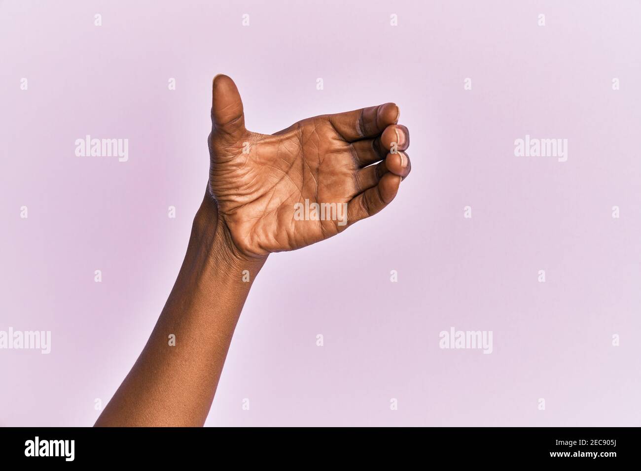 Arm and hand of black middle age woman over pink isolated background ...
