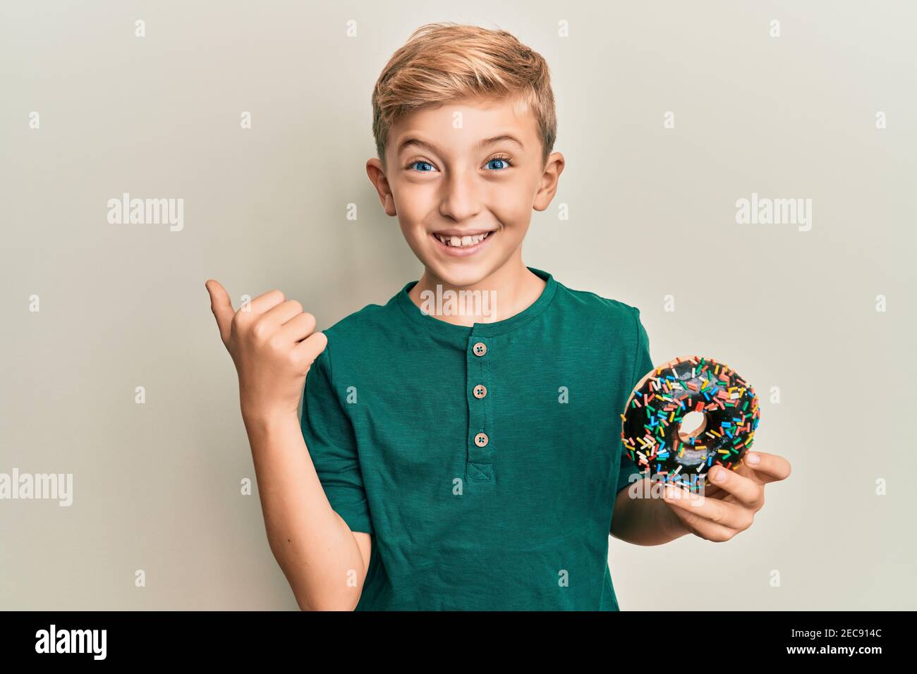 Little caucasian boy kid holding chocolate doughnut pointing thumb up ...